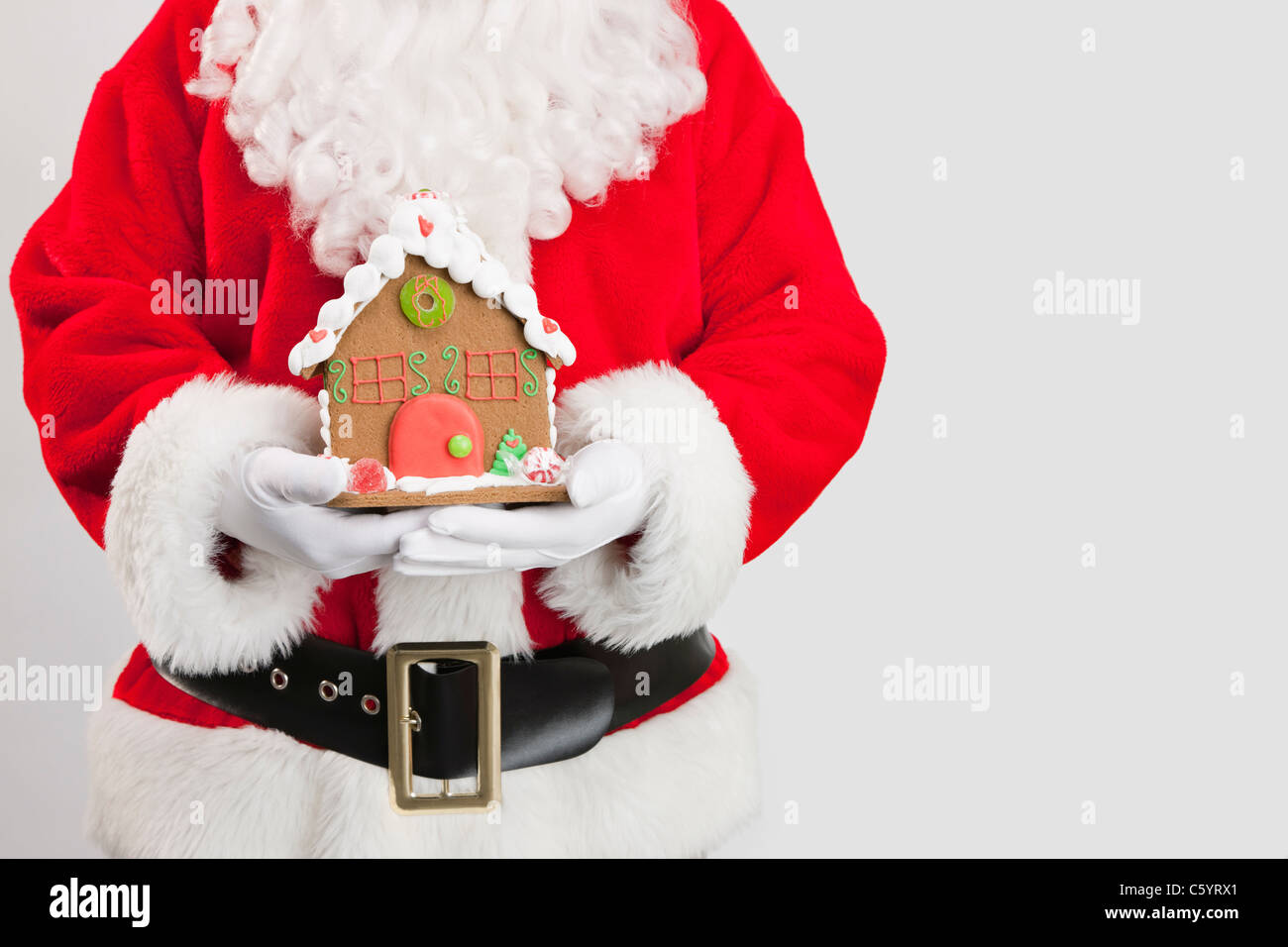 Santa clause holding gingerbread house Stock Photo - Alamy