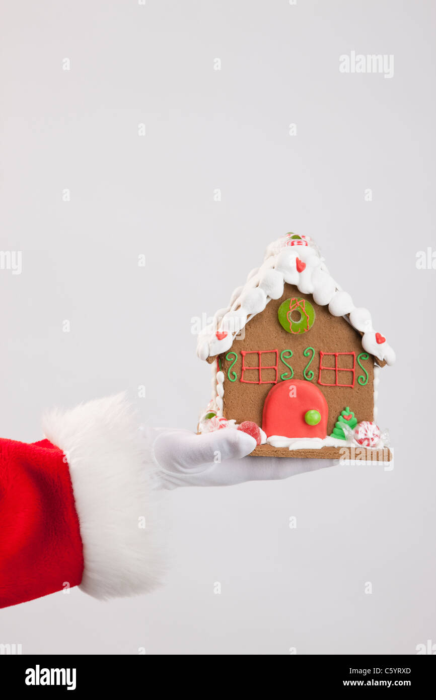 Santa clause holding gingerbread house Stock Photo - Alamy