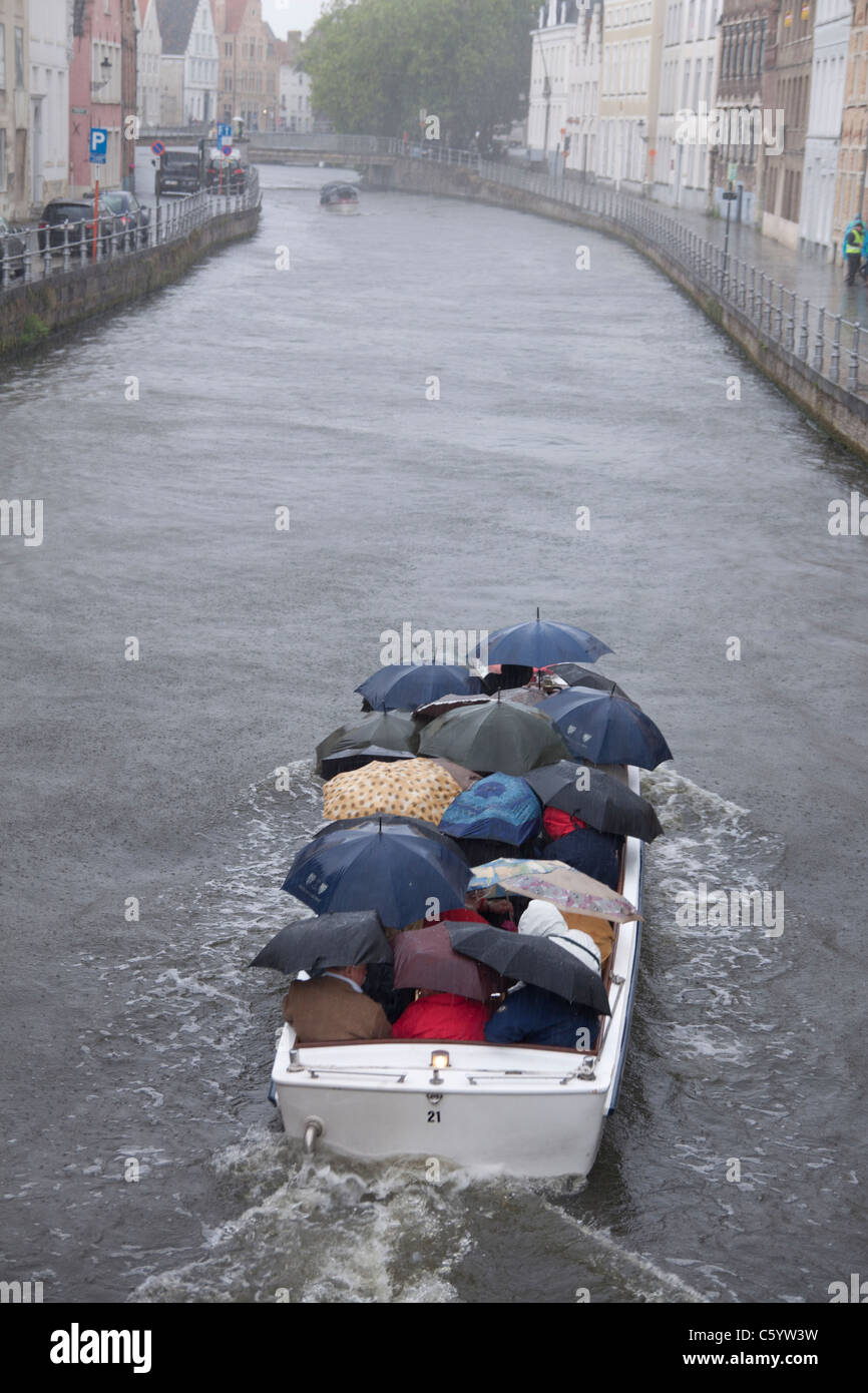 Tourists take a river cruise along the river in the rain in Bruges ...