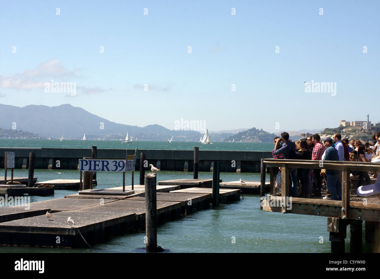 Tourists look out onto the San Francisco Bay from Pier 39 with Alcatraz ...