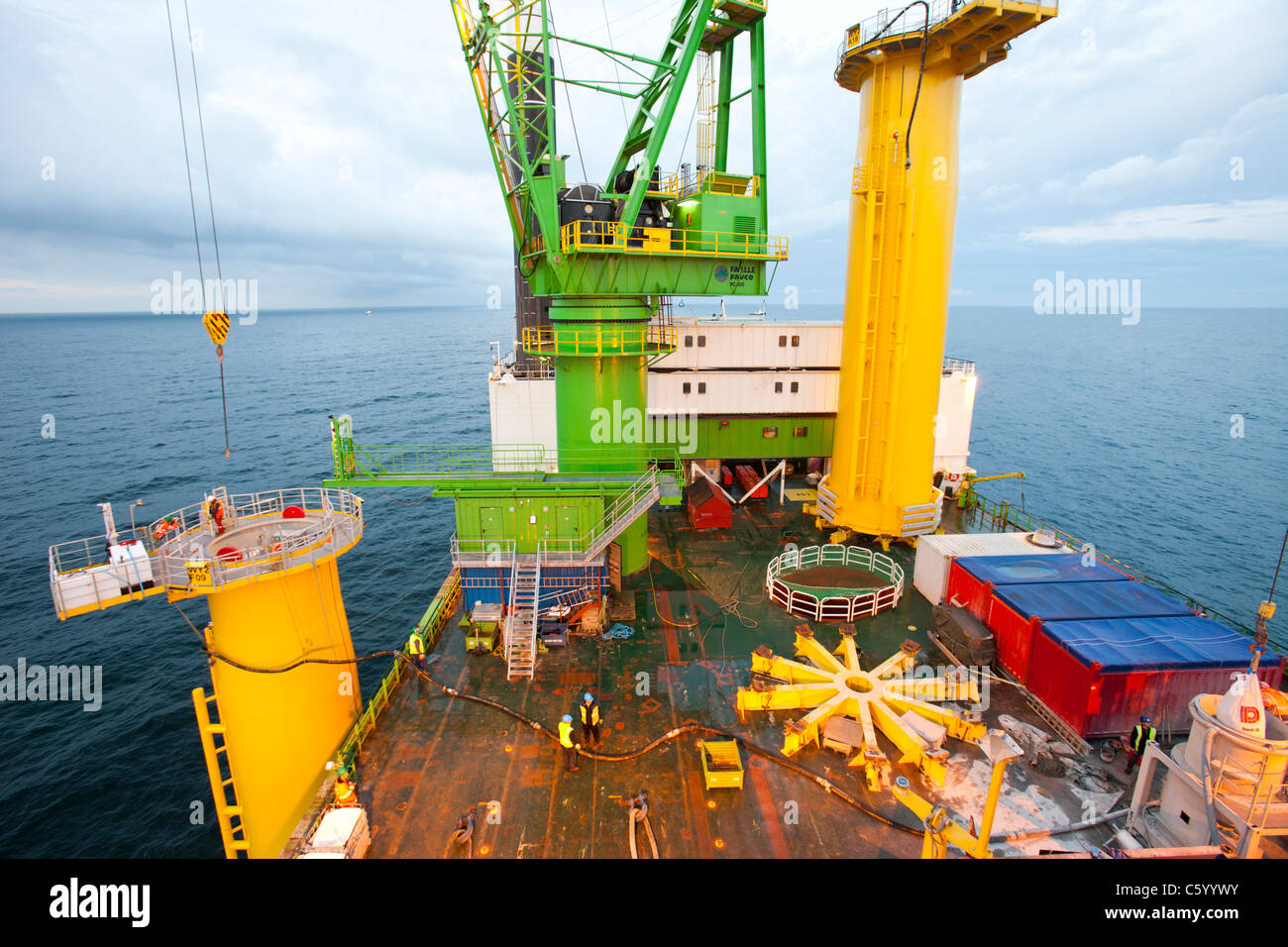 A crane lifts a transition piece into place at dawn on the Walney ...