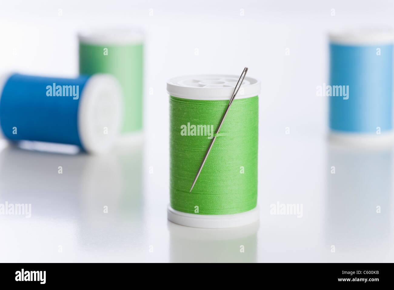 Blue and green threads with needle Stock Photo - Alamy