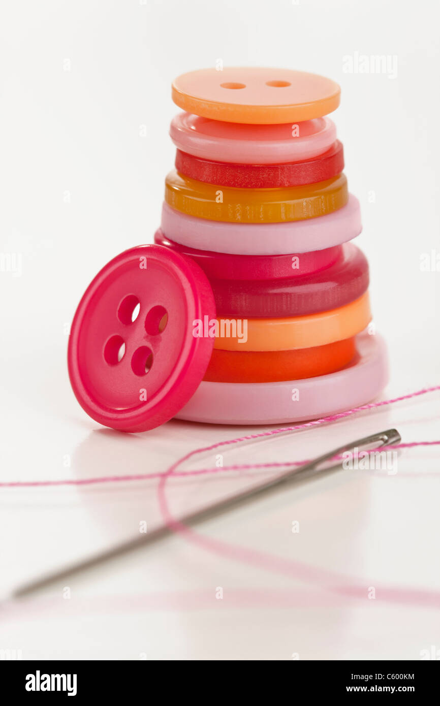 Stacked buttons with needle and thread Stock Photo - Alamy