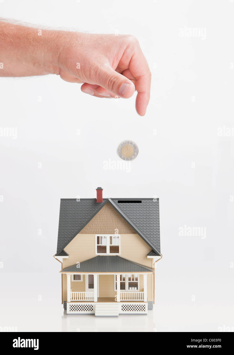 Close up of man's hand throwing coin into model house Stock Photo - Alamy