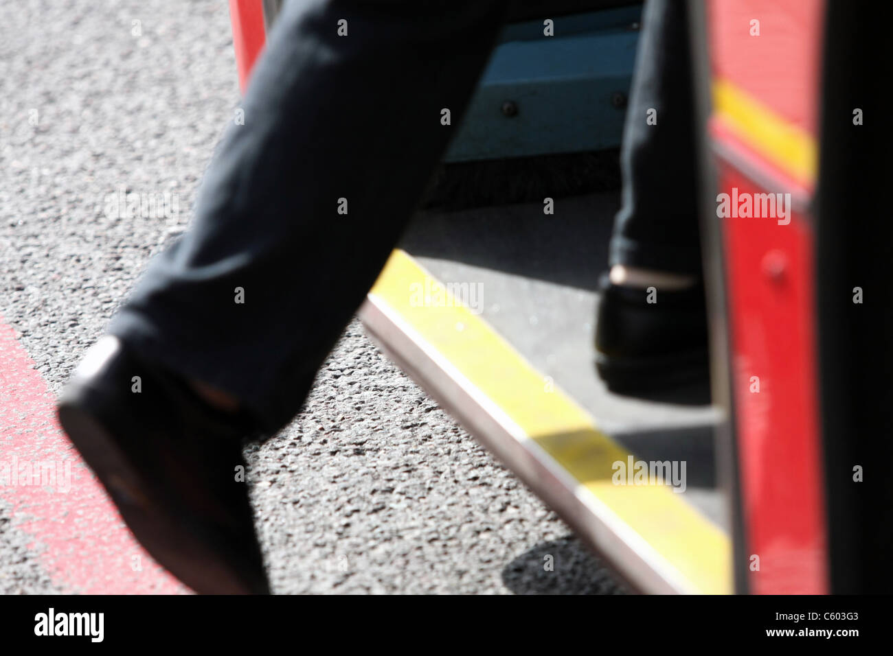 The legs of a person boarding a red London bus at a bus stop Stock ...