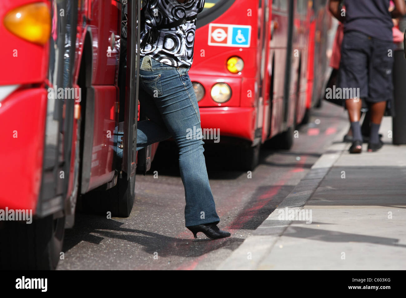 A lady stepping off a red London bus at a bus stop Stock Photo - Alamy