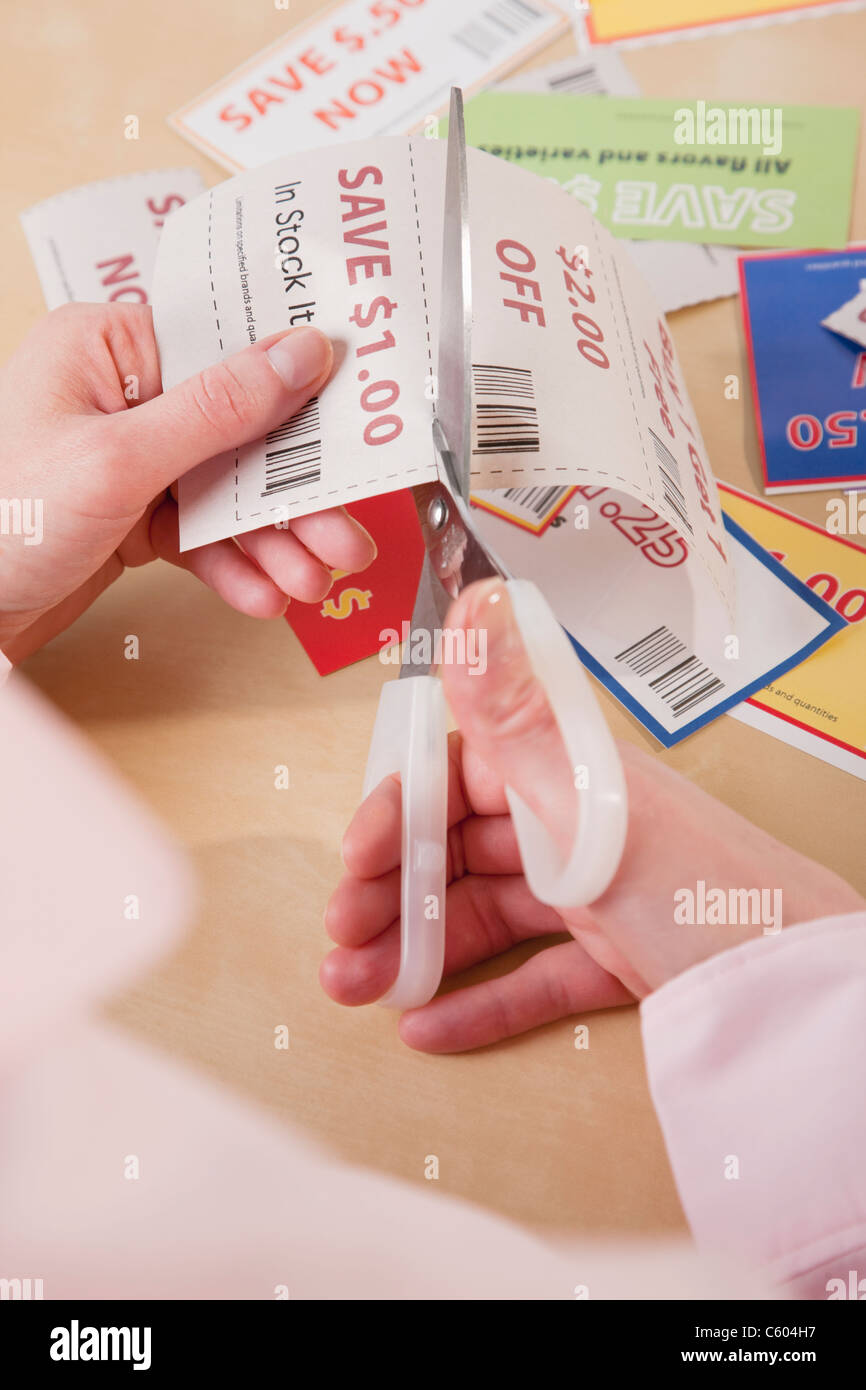 Hands cutting out coupon Stock Photo - Alamy