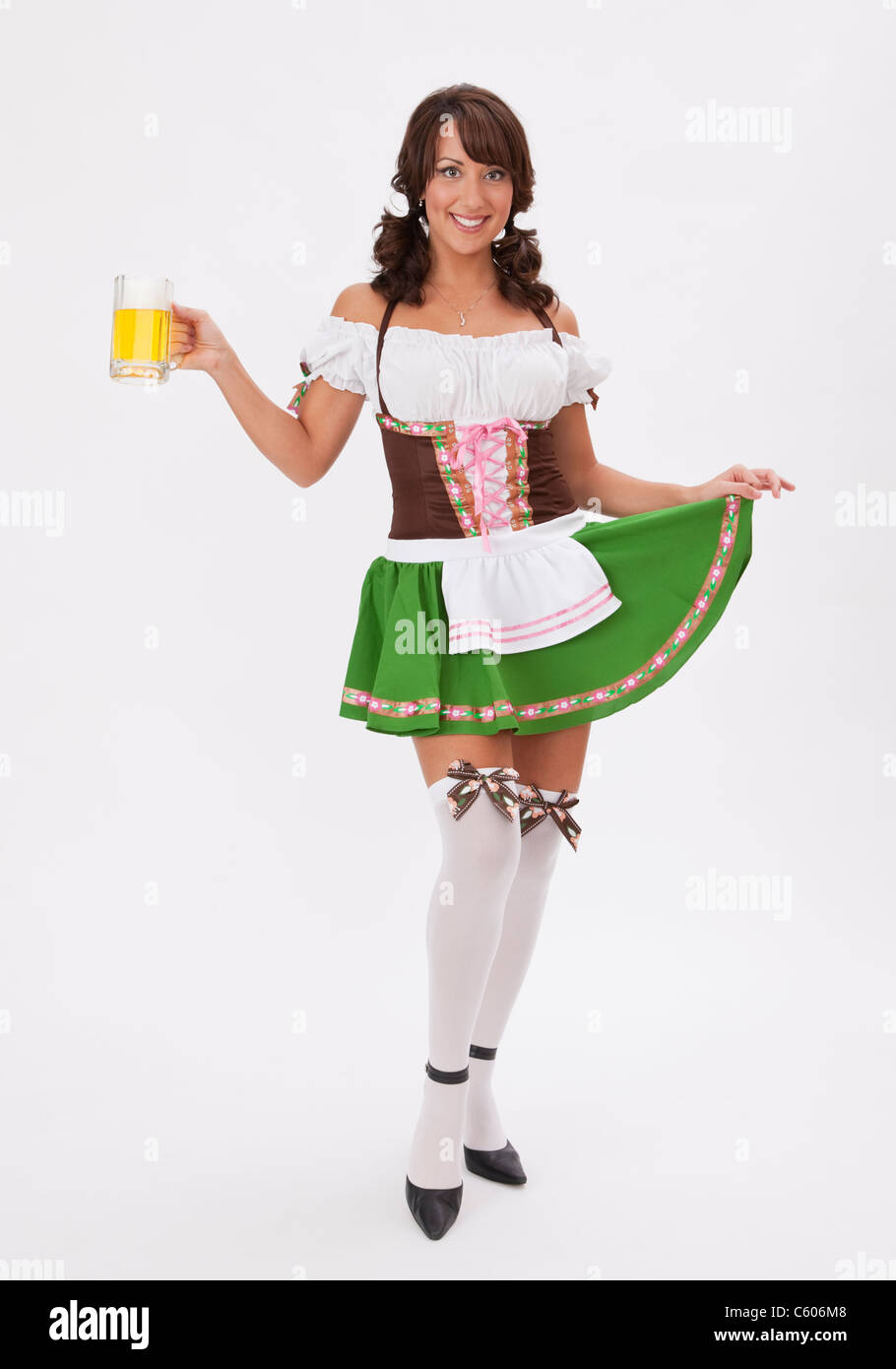 Young woman wearing Oktoberfest costume holding beer stein, studio shot ...