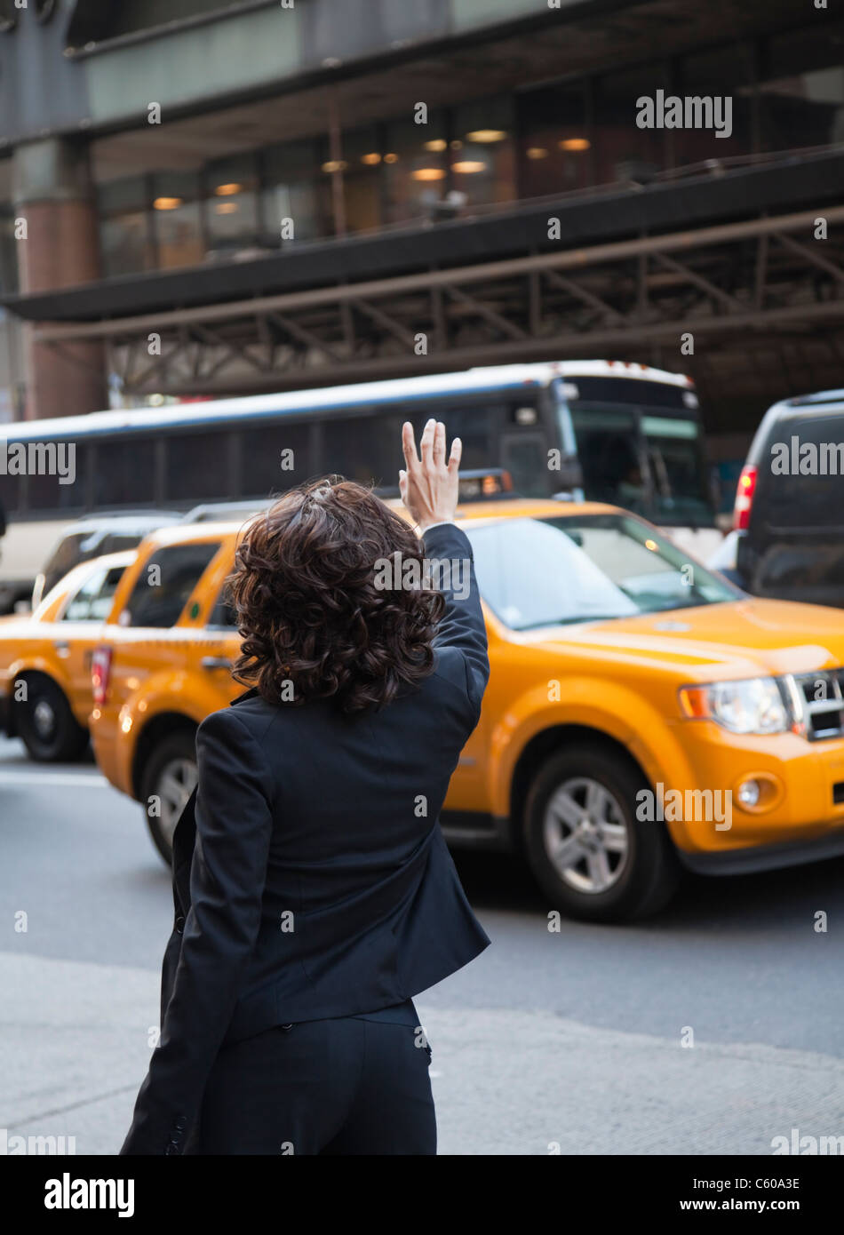 USA, New York, New York City, rear view of woman hailing taxi Stock ...