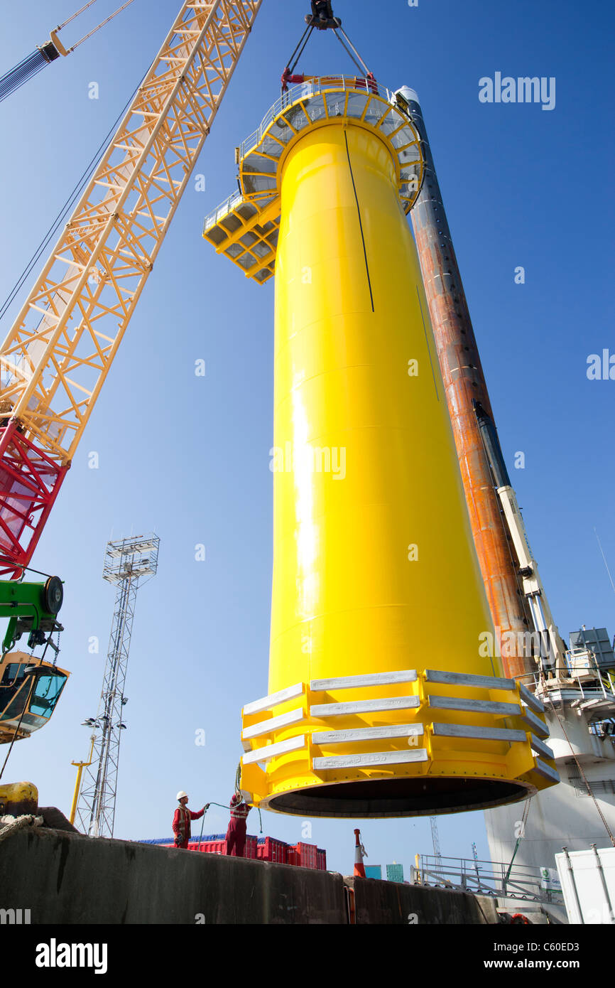 A crane lifts a transition piece of a wind turbine onto a jack up barge ...