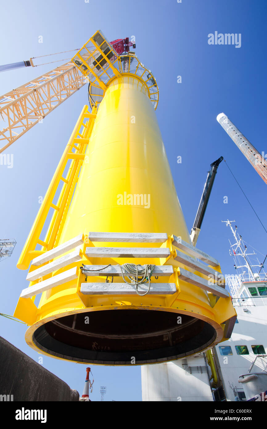 A crane lifts a transition piece of a wind turbine onto a jack up barge ...