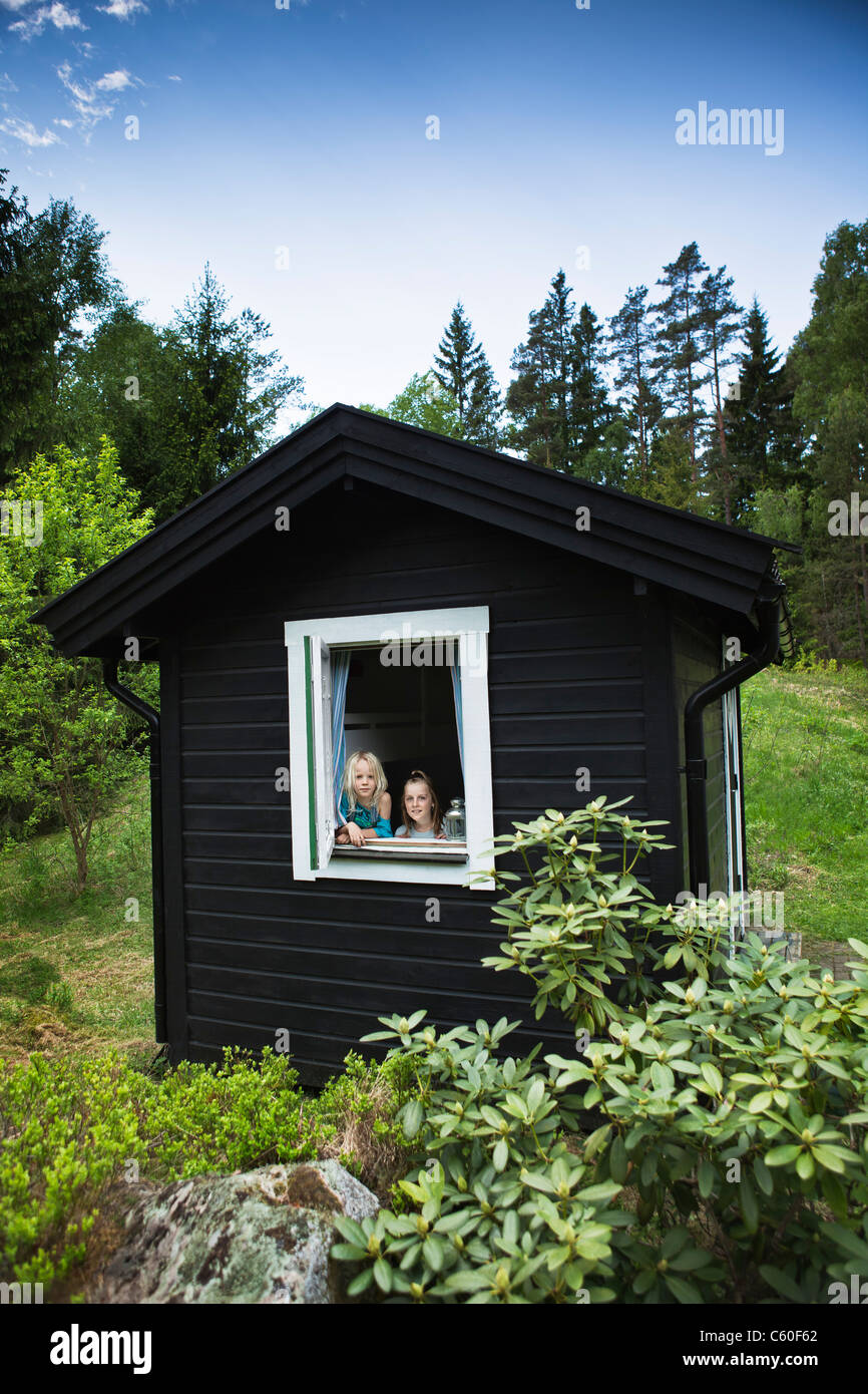 Girls looking out window of shack Stock Photo - Alamy