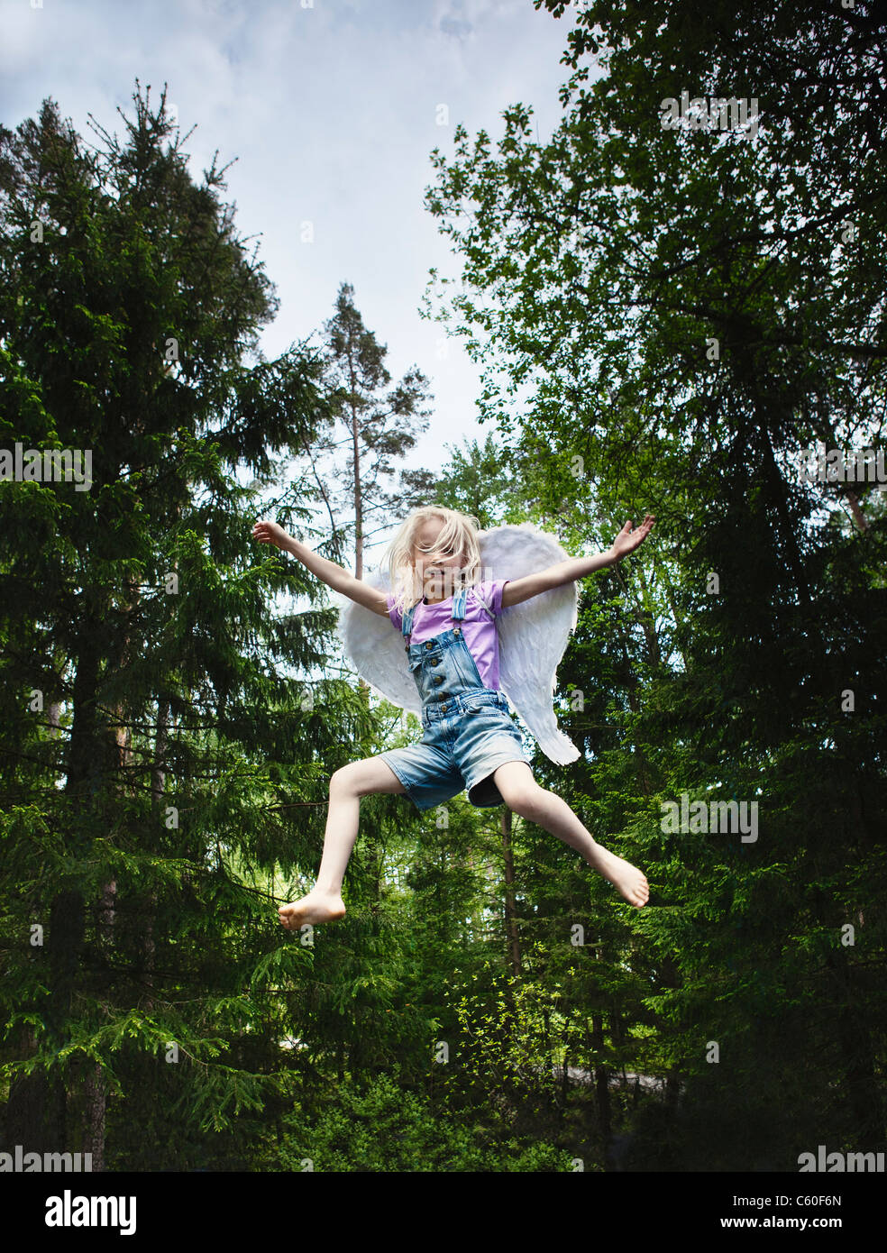 Girl wearing wings and jumping in forest Stock Photo - Alamy