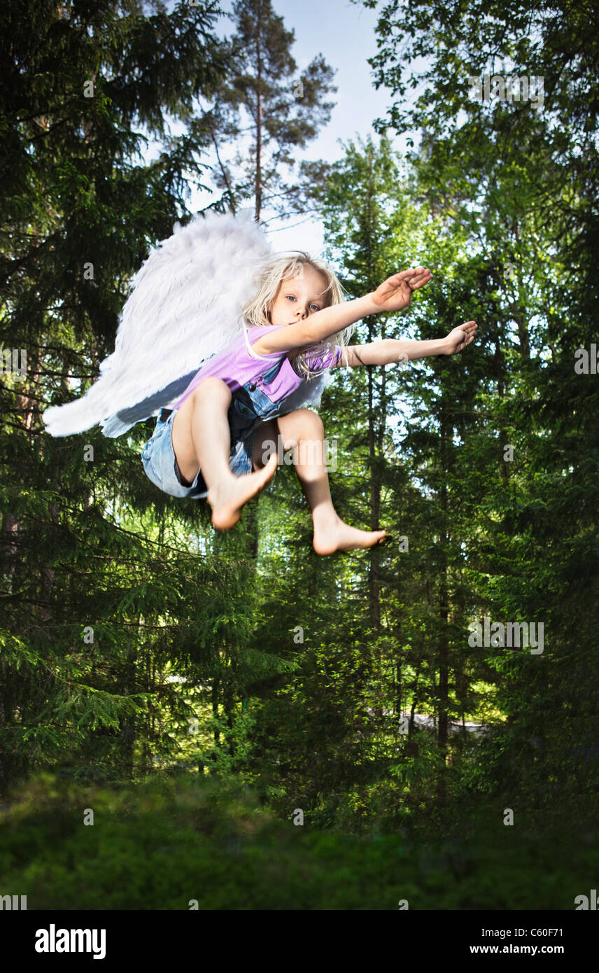 Girl wearing wings and jumping in forest Stock Photo - Alamy