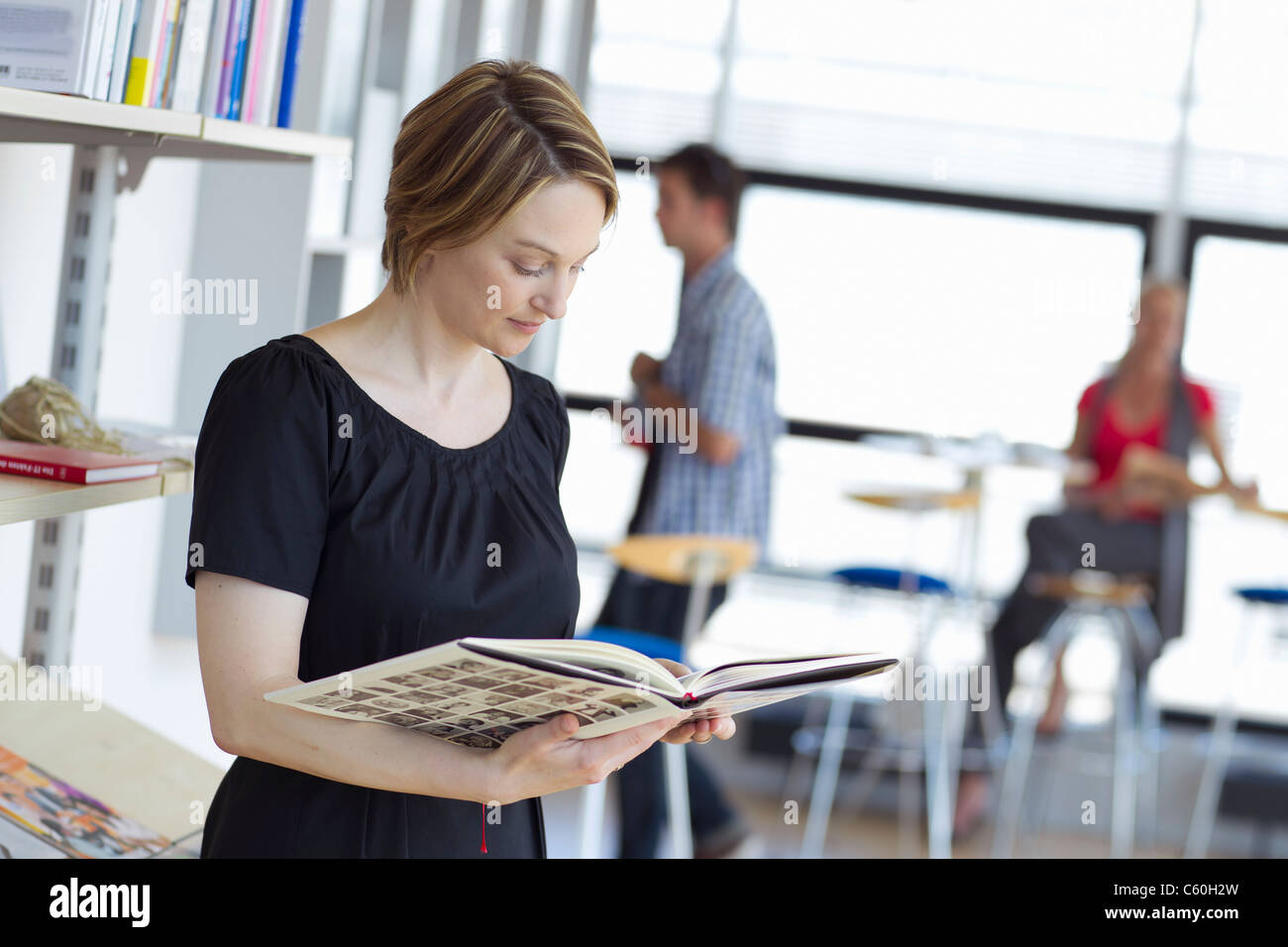 Woman reading book in library Stock Photo - Alamy