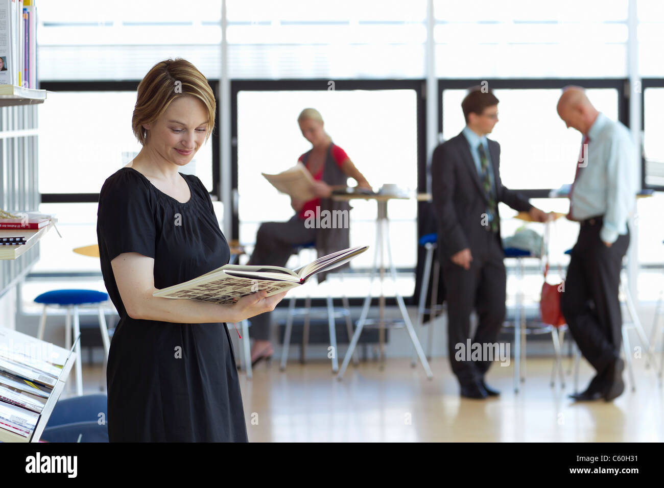 Woman reading book in library Stock Photo - Alamy
