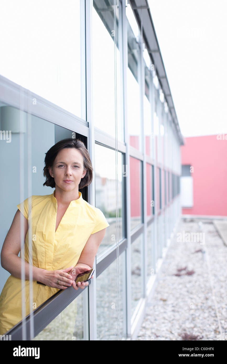 Businesswoman leaning out office window Stock Photo - Alamy