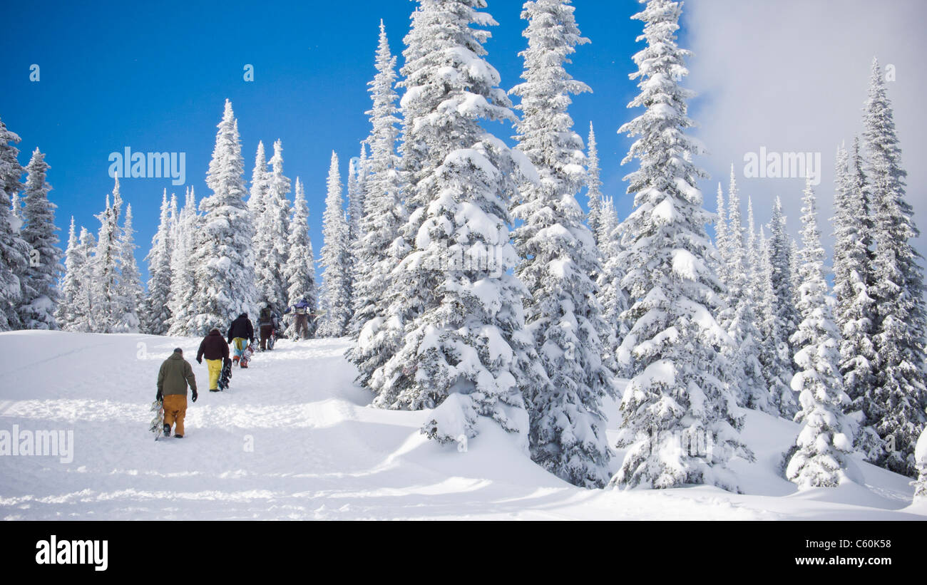 Snowboarders walking up hillside Stock Photo - Alamy