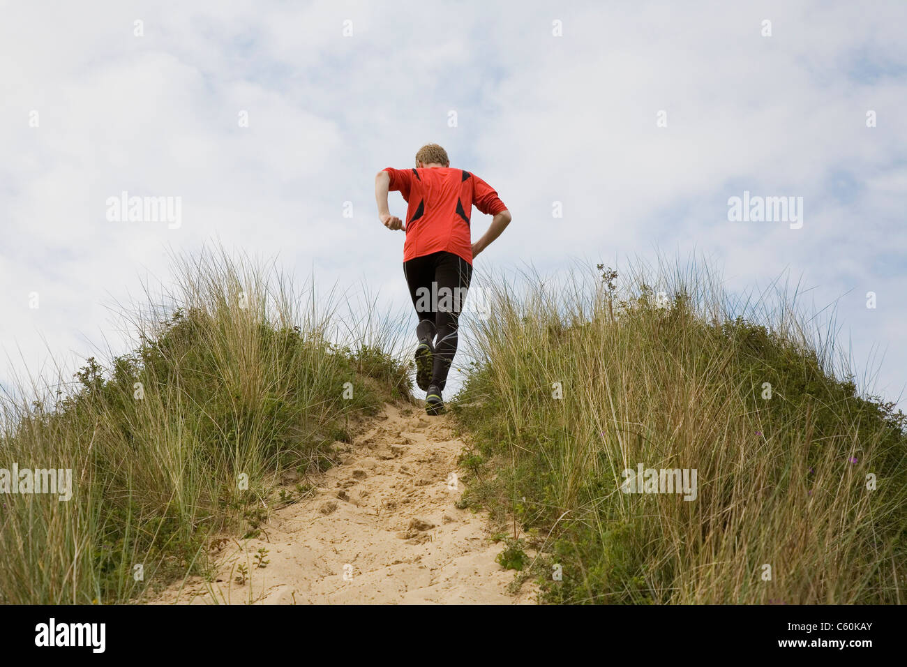 Man running up grassy hillside Stock Photo - Alamy