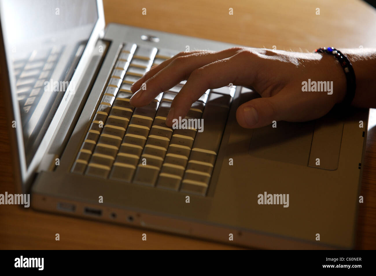 Hand poised above a laptop placed on a desk Stock Photo - Alamy