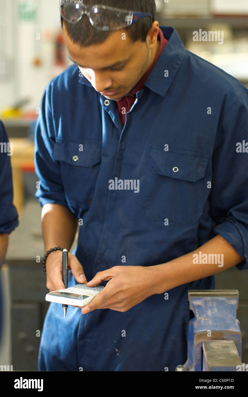 Worker using calculator in factory Stock Photo - Alamy