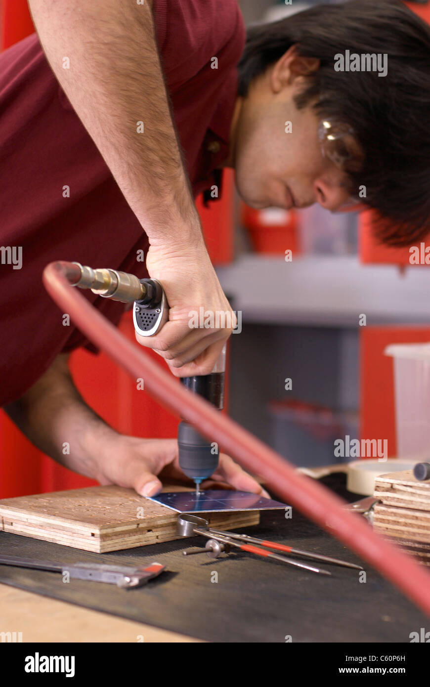 Worker using drill in factory Stock Photo - Alamy