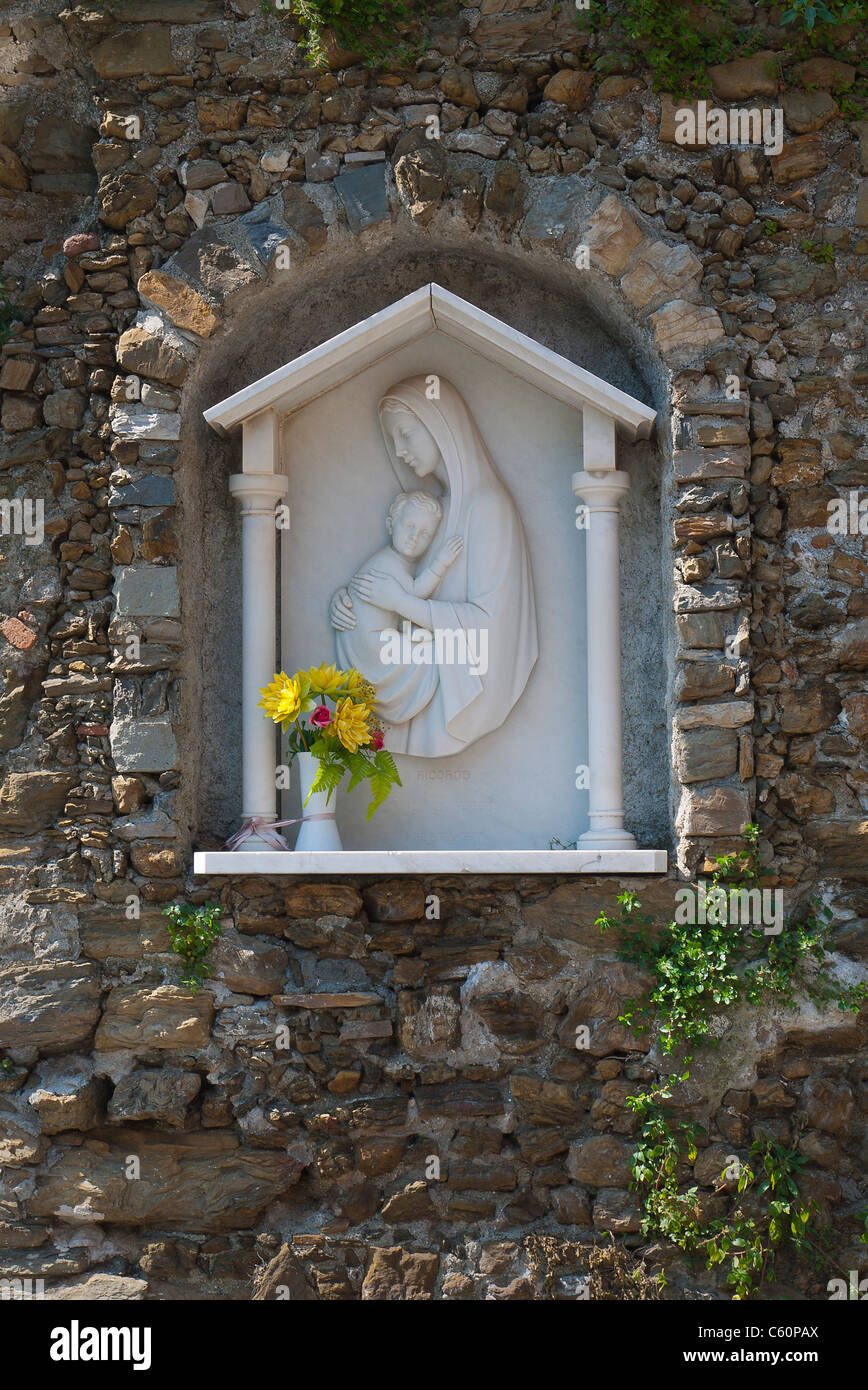 Madonna and Child marble shrine set in a stone wall with fresh flowers ...