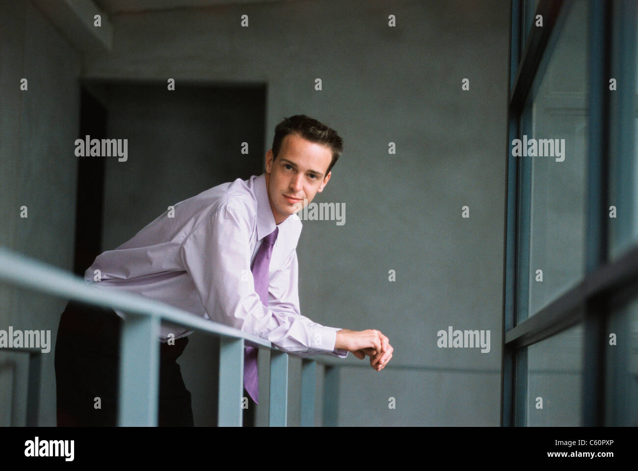 Businessman leaning on railing Stock Photo - Alamy