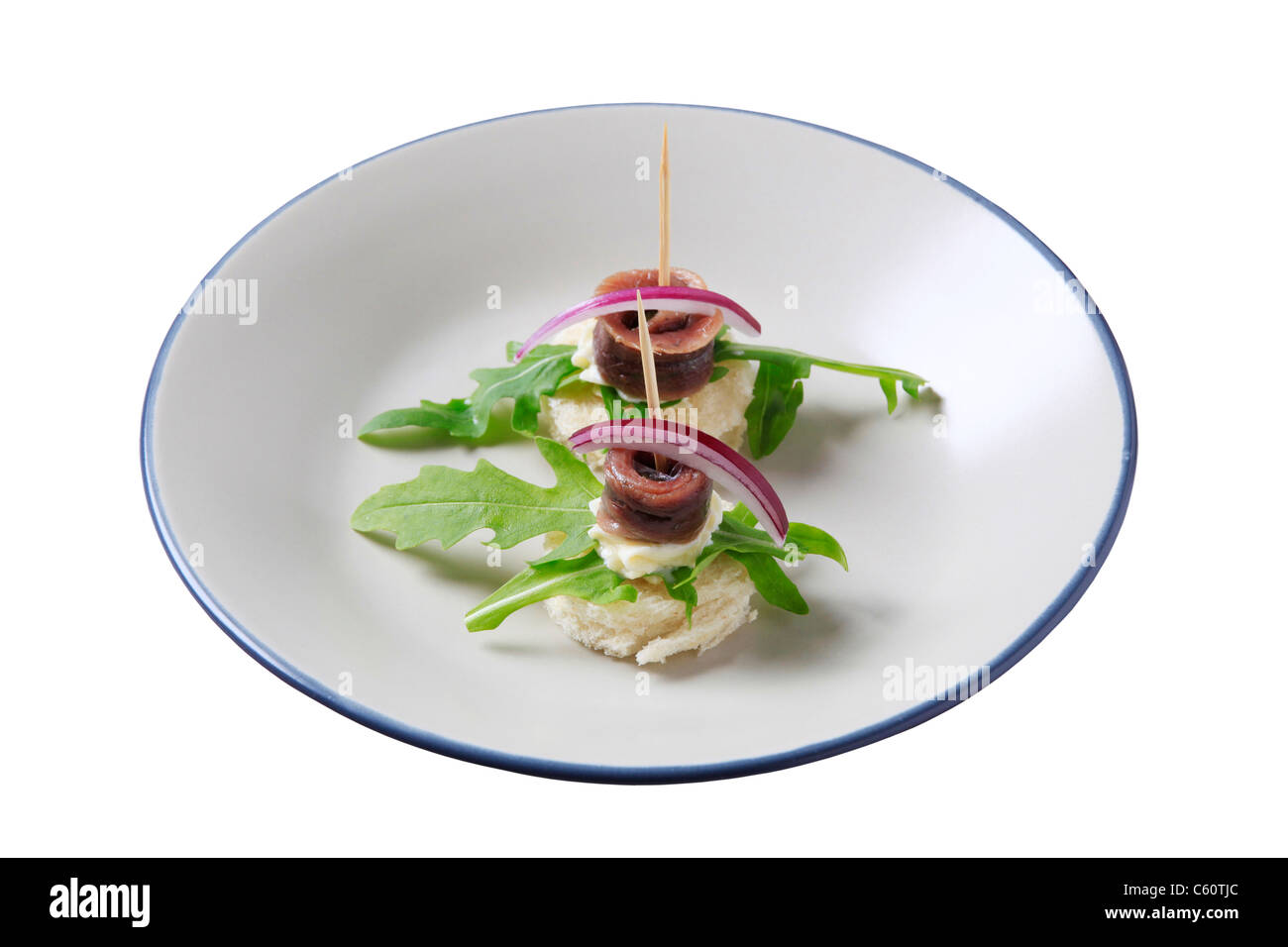 Anchovy canapes garnished with arugula and onion Stock Photo - Alamy