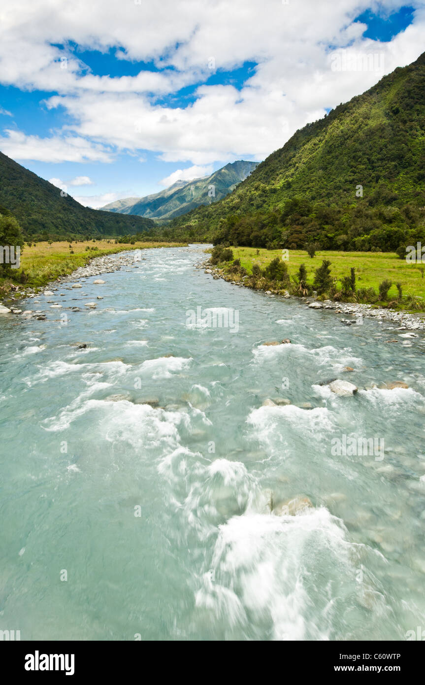 river flowing through a valley with mountain massive in the back ground ...