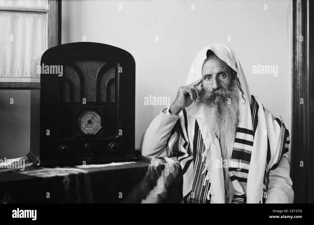 Yemenite Rabbi, in traditional robes and prayer shawl, listening to ...
