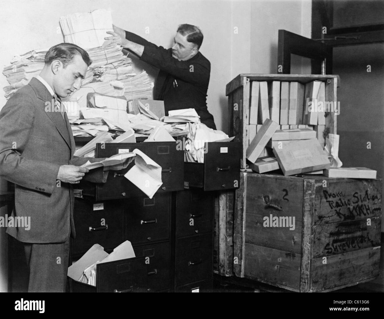 Two employees of the Federal Radio Commission overwhelmed by piles of ...