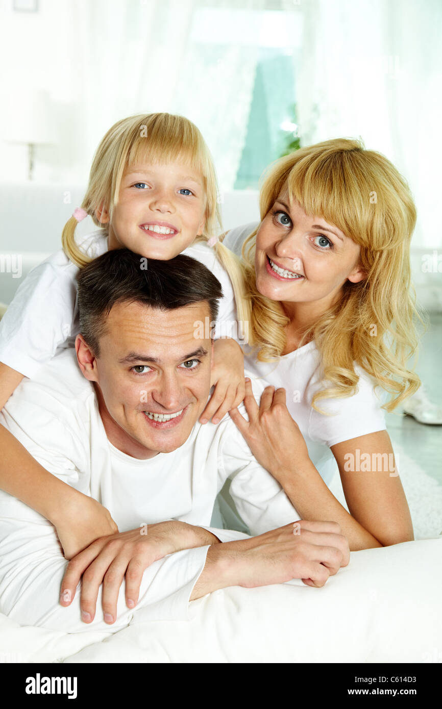 Portrait of happy parents with their daughter looking at camera at home ...