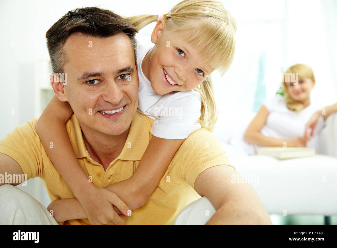 Portrait of happy father holding daughter on back and both looking at ...