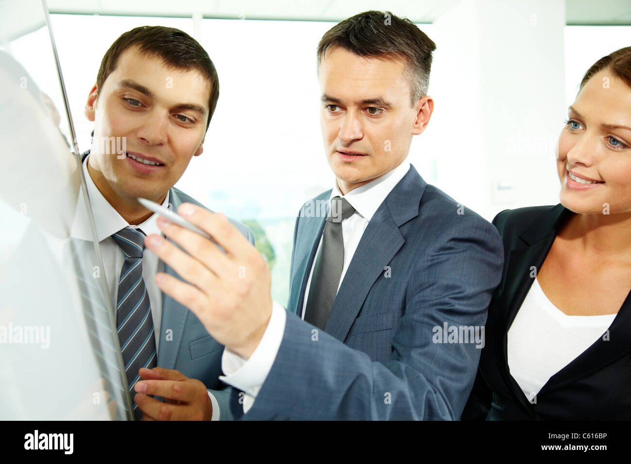 A business man explaining something on a whiteboard to his partners ...