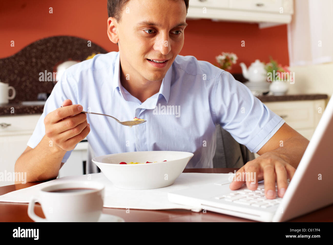 Portrait of handsome man eating snacks with milk in the kitchen while ...