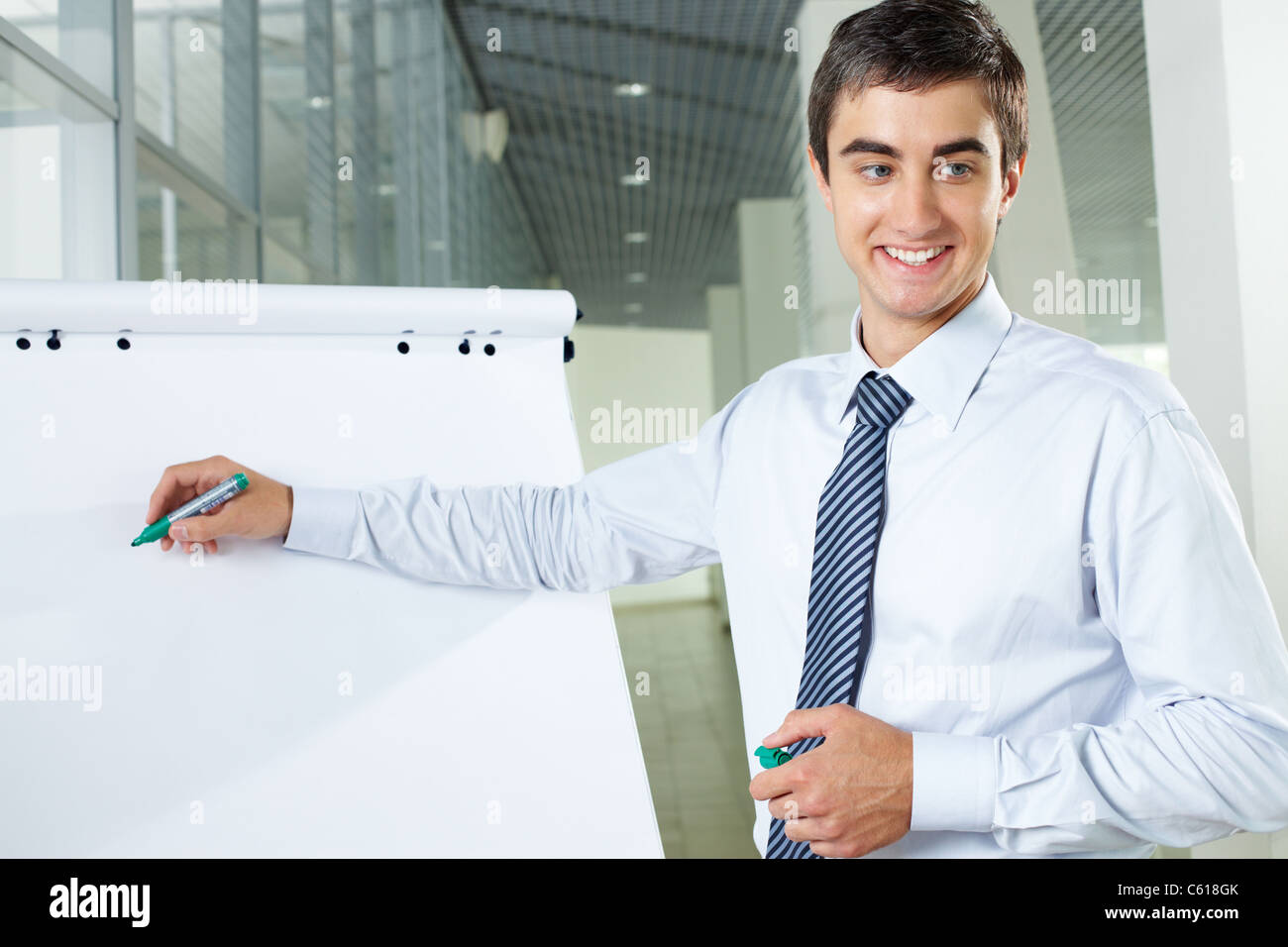 Smiling businessman presenting new project to partners on a whiteboard ...