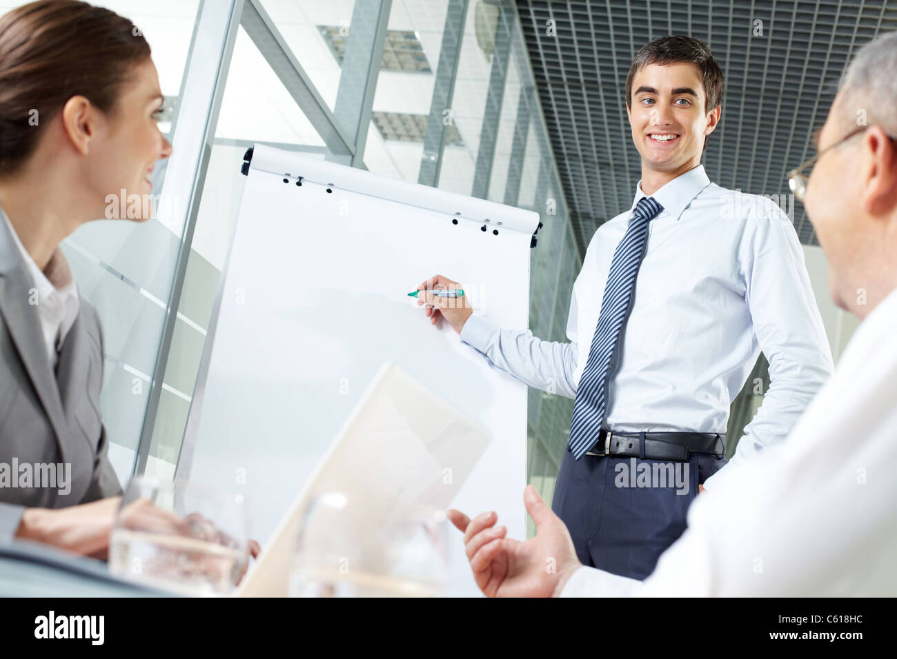 Smiling business man presenting new project to his partners on a ...