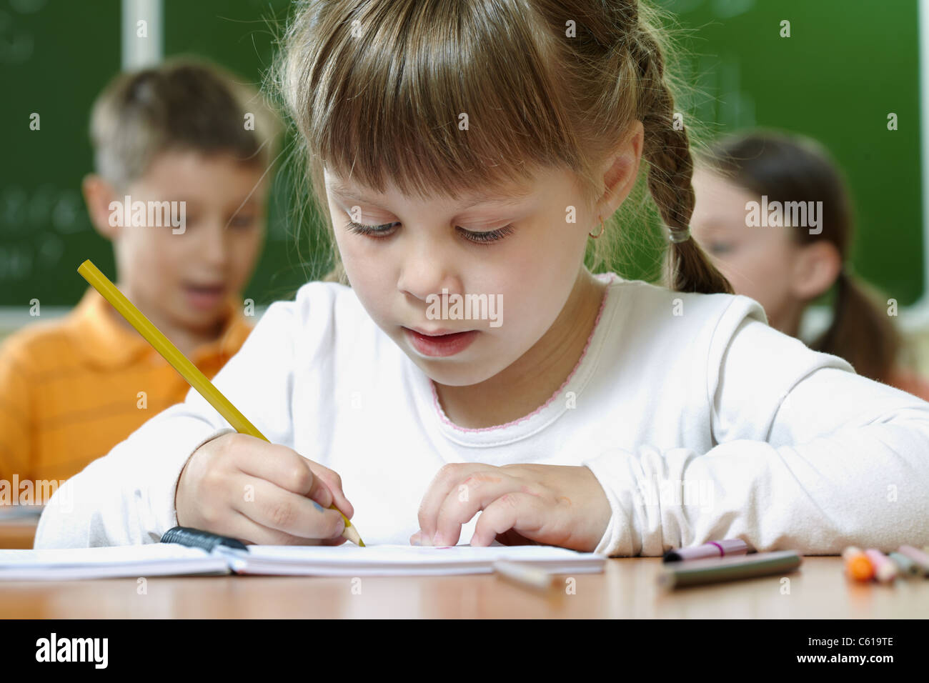 Portrait of smart schoolgirl drawing at lesson in classroom Stock Photo ...