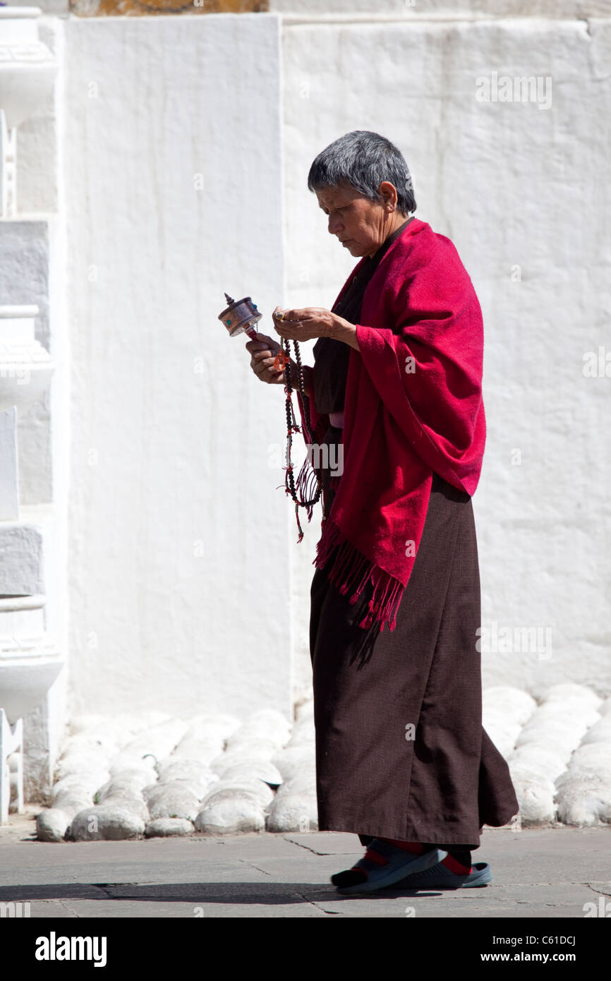 Bhutanese woman at morning prayers, walking clockwise around a chorten ...