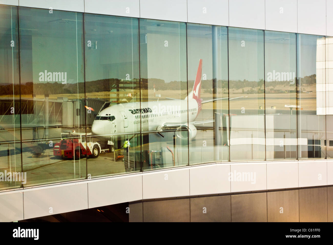 Qantas aircraft pushback reflected in terminal window Stock Photo - Alamy