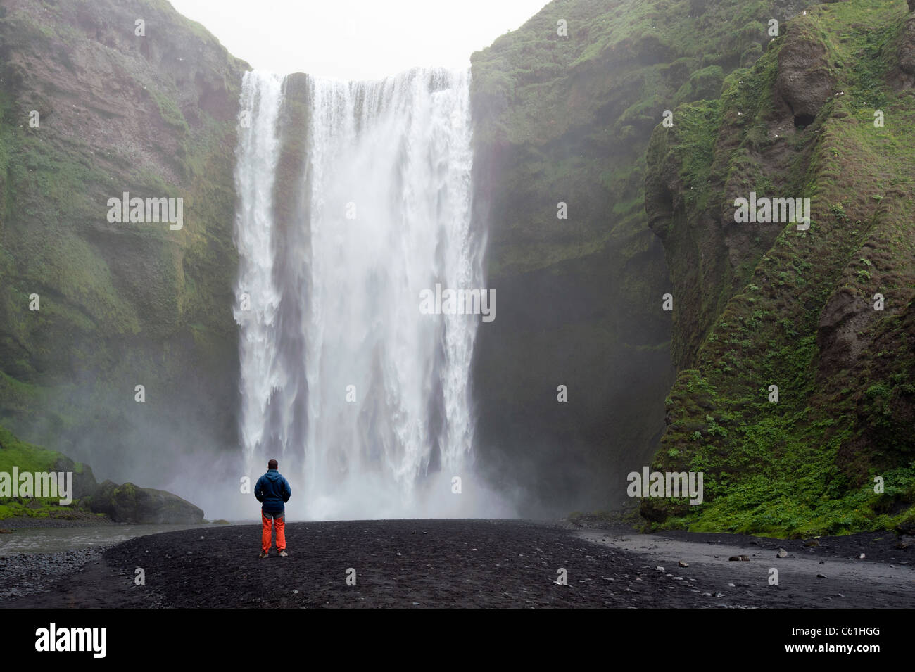 tourist in front of Skogafoss waterfall (lots of dust particles in the ...