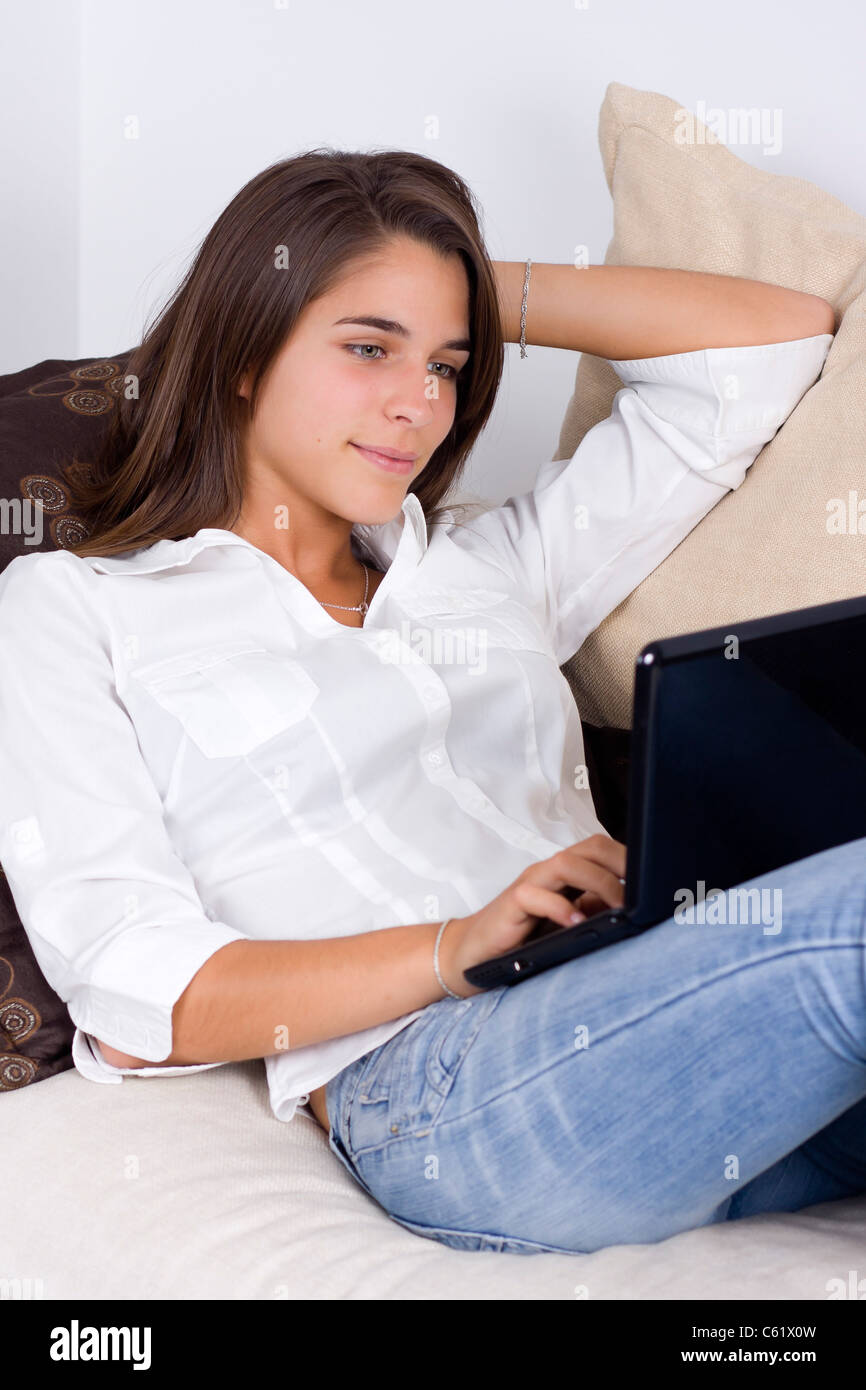 Attractive young woman using a laptop on a couch Stock Photo - Alamy