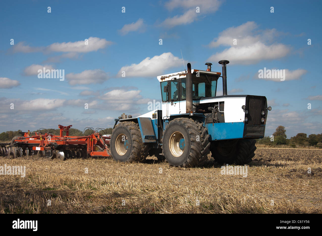 Tractor in field with blue sky and clouds Stock Photo - Alamy