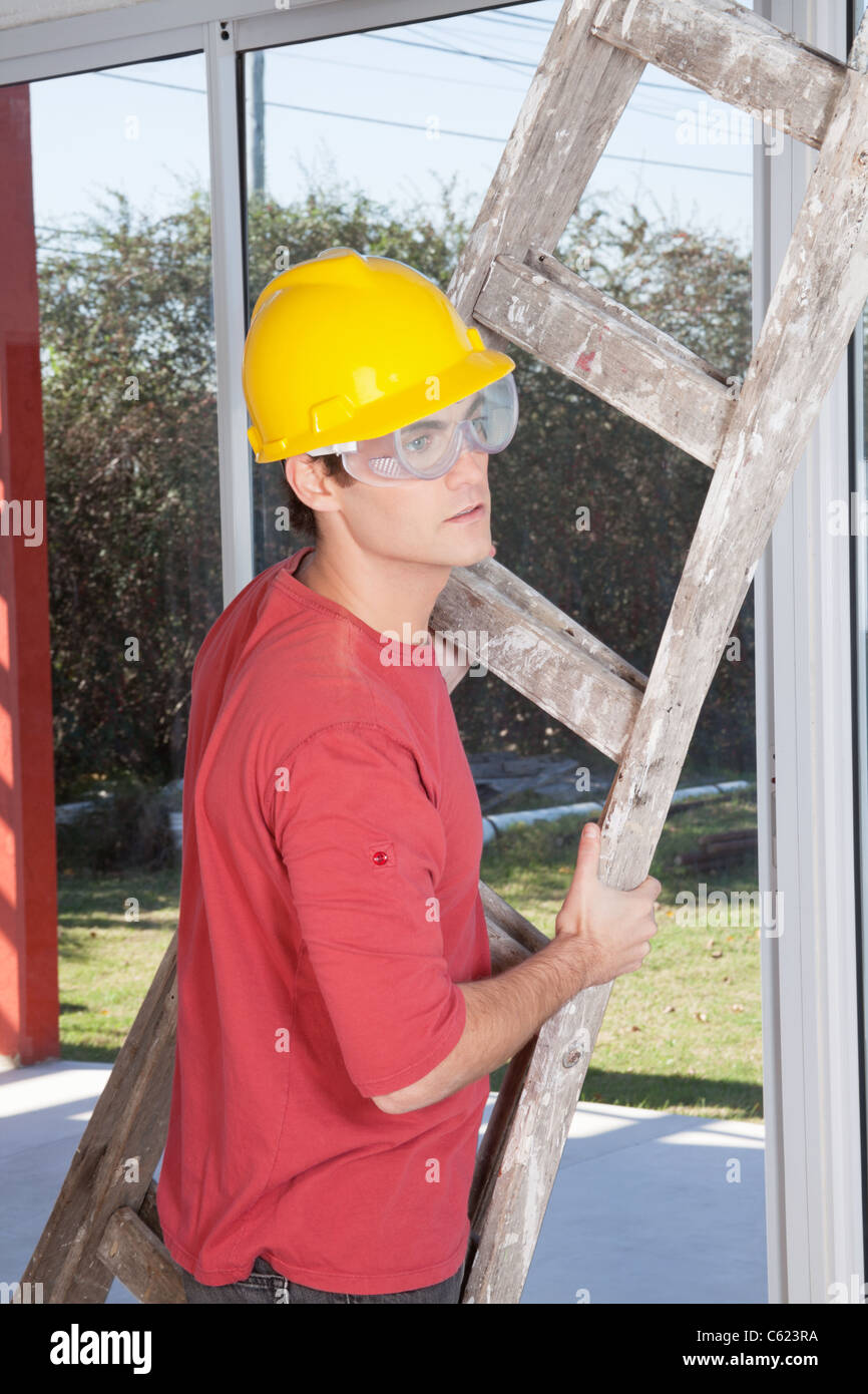 Male construction worker holding ladder in hand Stock Photo - Alamy