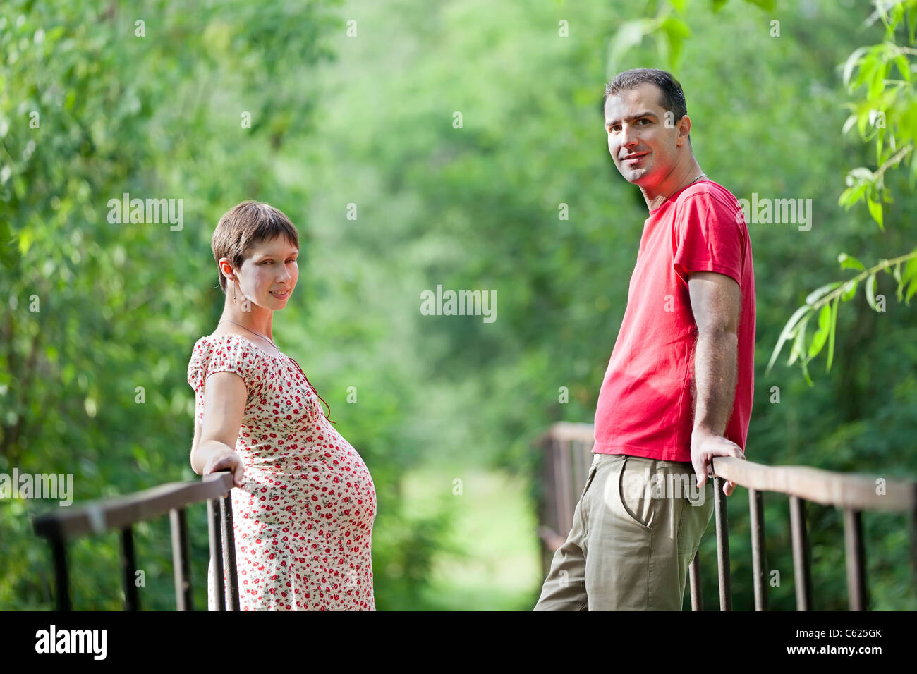 Husband with his pregnant wife on the bridge in green forest Stock ...