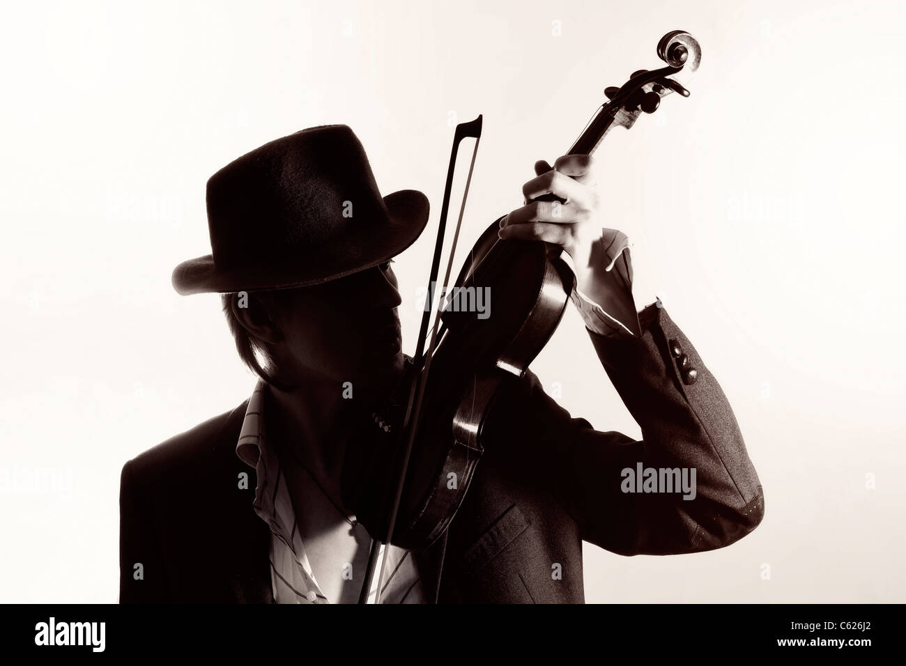 young violinist playing the violin in hat and jacket on a light ...