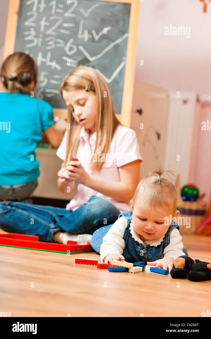 Children - sisters - playing at home; one child is still a baby Stock ...