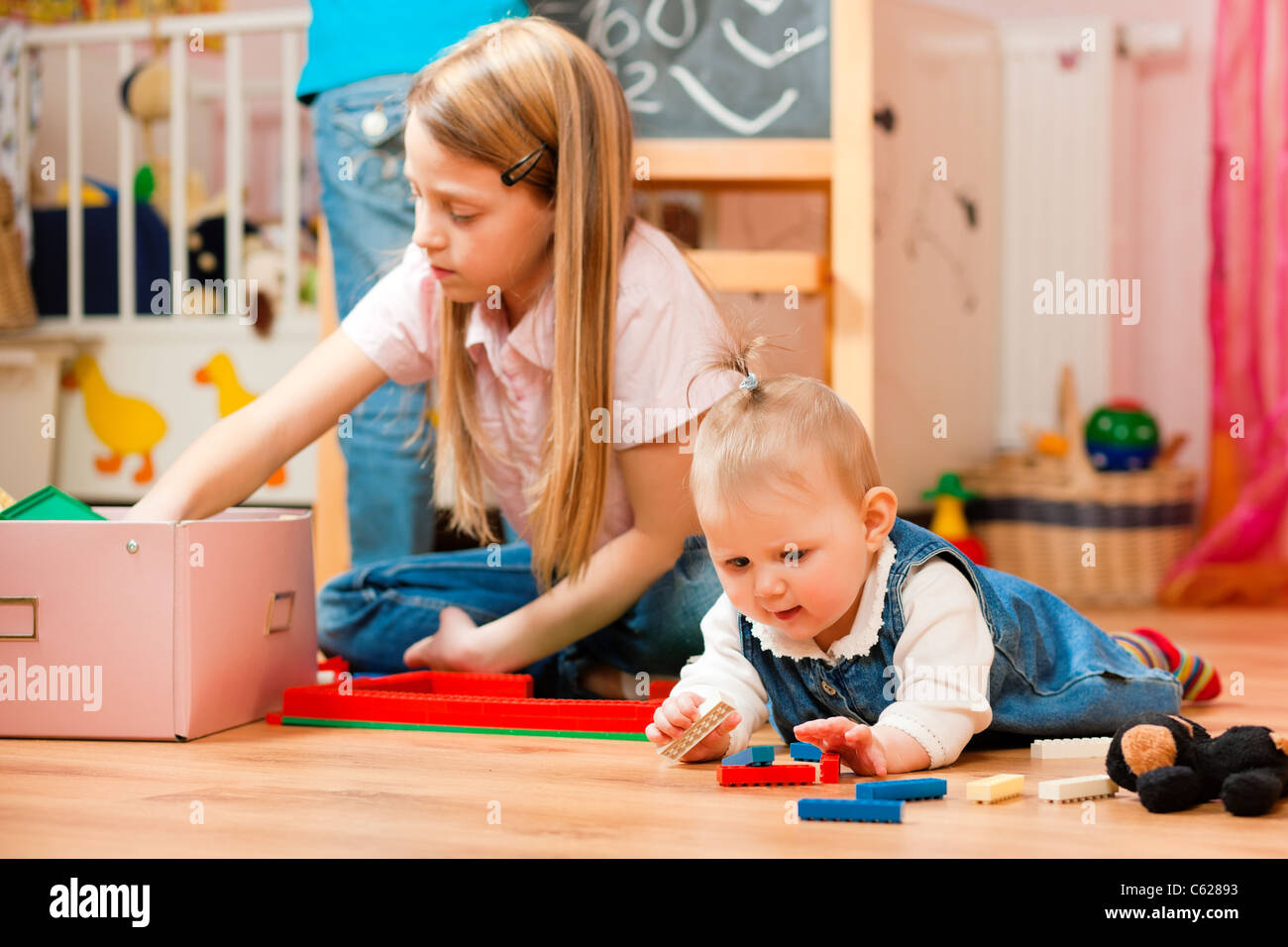 Children - sisters - playing at home; one child is still a baby Stock ...