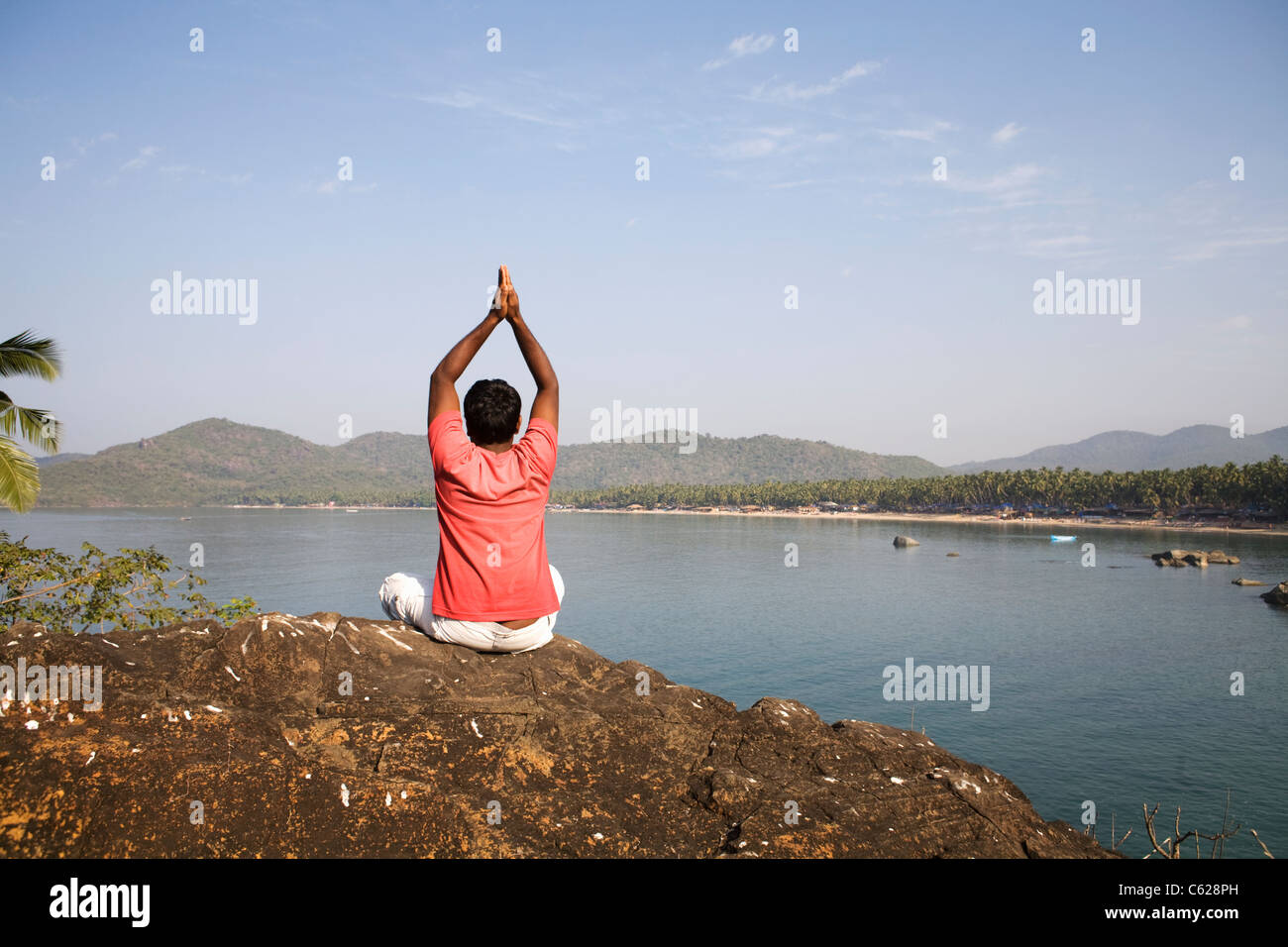 A man performs yoga meditation high over a tropical ocean Stock Photo ...